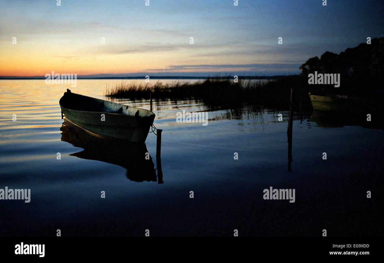 Film scan of a stationary boat facing vivid sunrise at tranquil lake ...