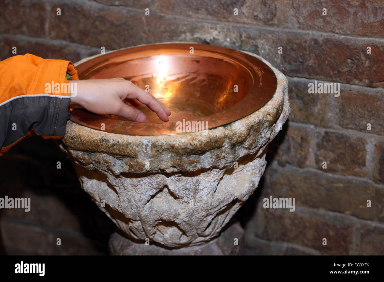 hand of child and an ancient holy water font inside the Church in a ...