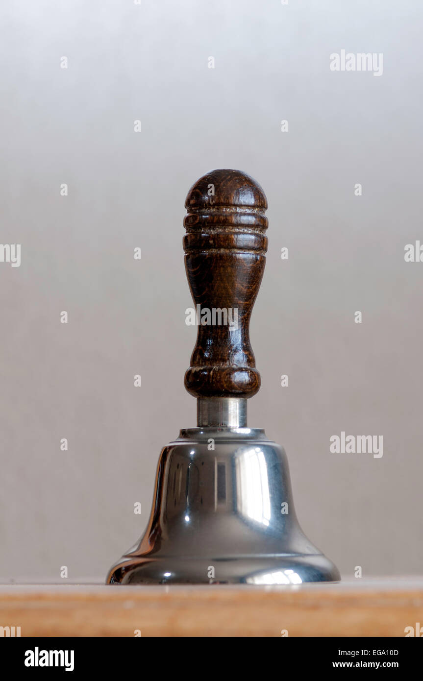 Replica of old school hand bell standing on a wooden board with a light ...