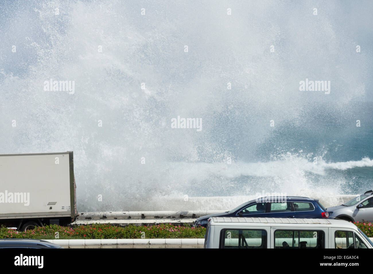 Waves crashing over sea wall onto road Stock Photo - Alamy