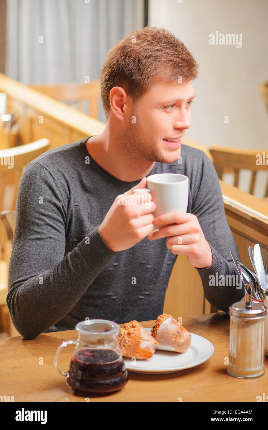 Inspired by cup of fresh coffee. Handsome young man enjoying coffee in ...