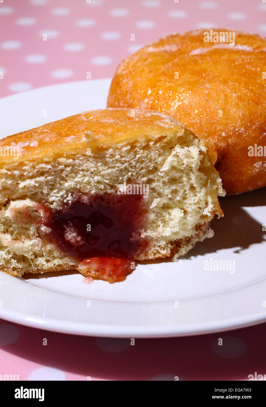 Doughnut on plate cut in half with jam oozing out Stock Photo - Alamy