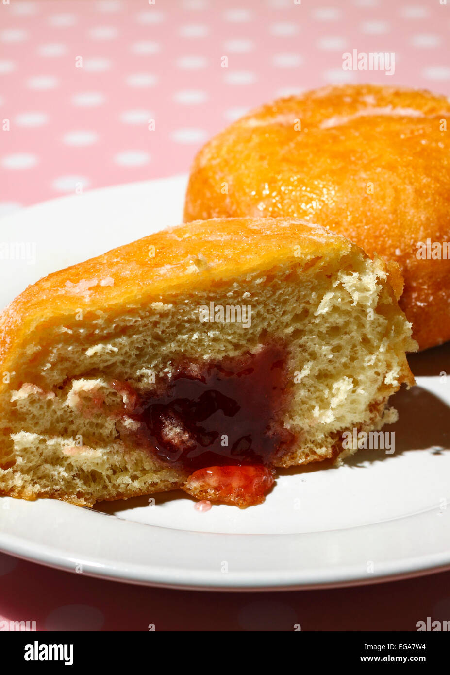 Doughnut on plate cut in half with jam oozing out Stock Photo - Alamy