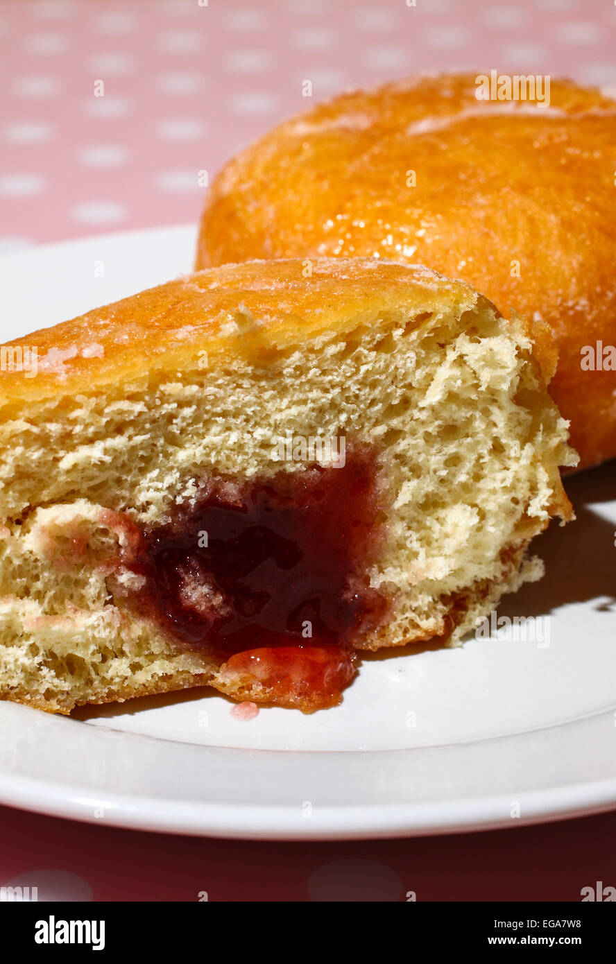 Doughnut on plate cut in half with jam oozing out Stock Photo - Alamy