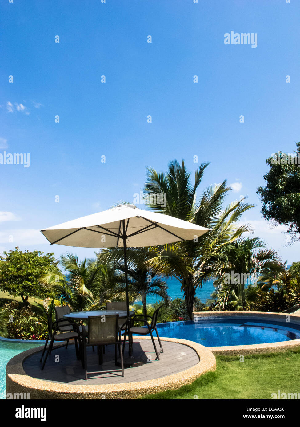 A nice welcoming jacuzzi beside an umbrella and a swimming pool invites ...