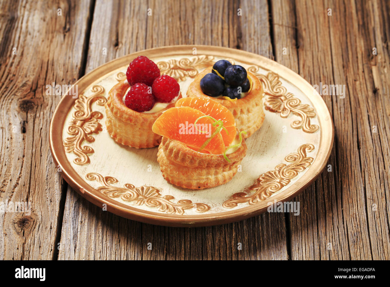 Custard filled puff pastry shells topped with fresh fruit Stock Photo ...