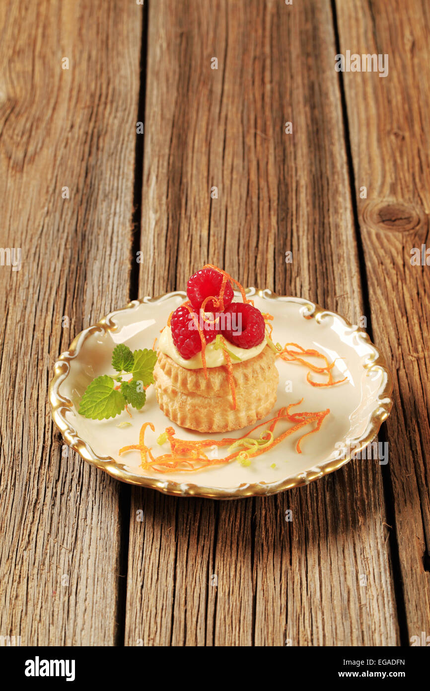 Custard filled puff pastry shell topped with raspberries Stock Photo ...
