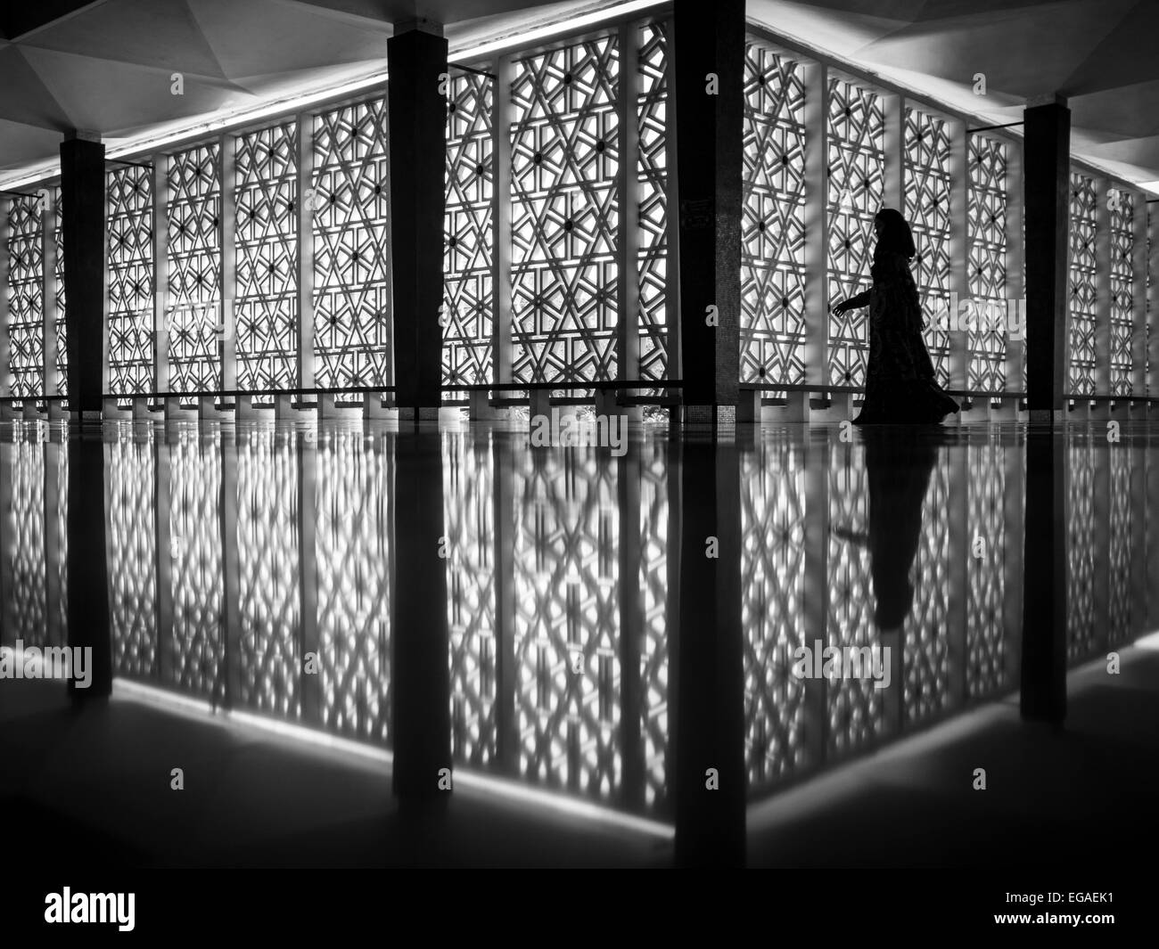 Silhouette of a Muslim woman walking pass Islamic design walls inside a ...