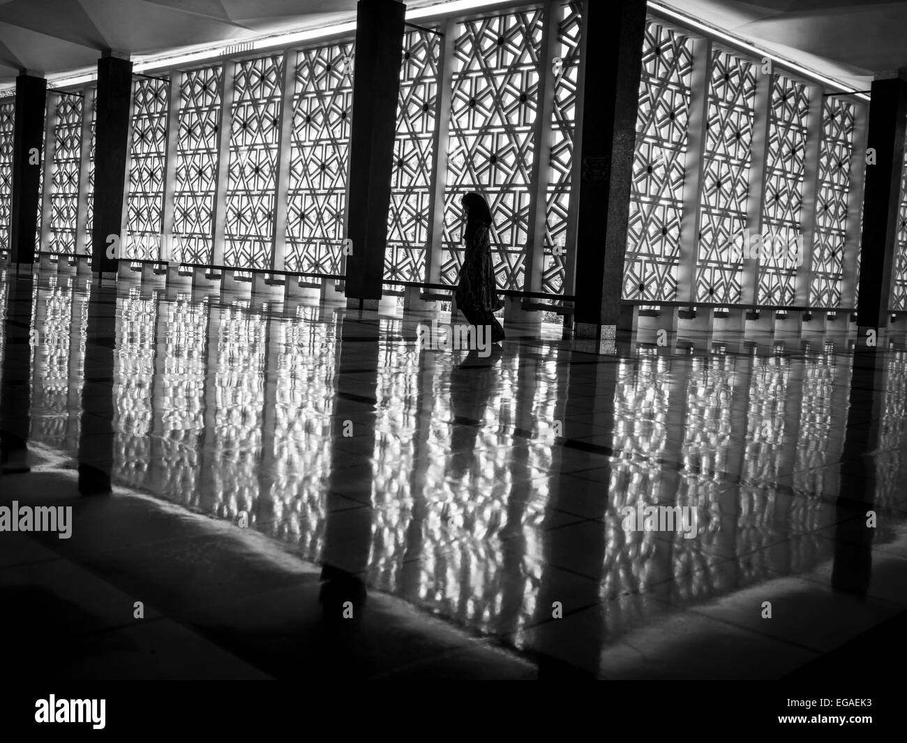 Silhouette of a Muslim woman walking pass Islamic design walls inside a ...