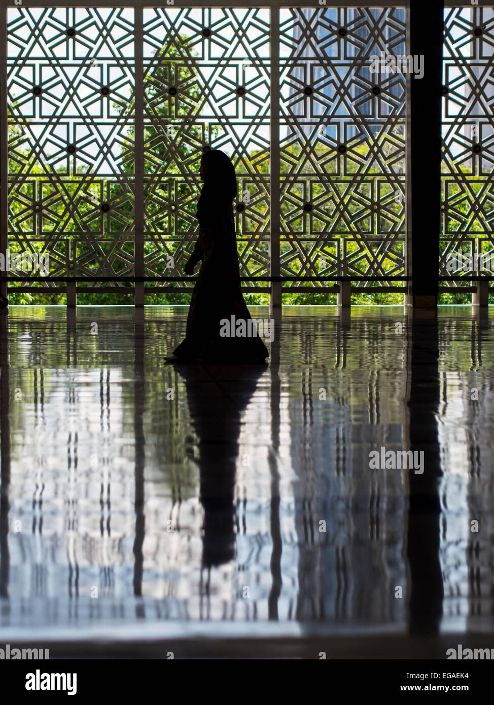 Silhouette of a Muslim woman walking pass Islamic design walls inside a ...