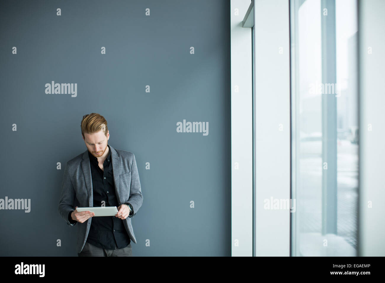 Young man with tablet by the wall Stock Photo - Alamy