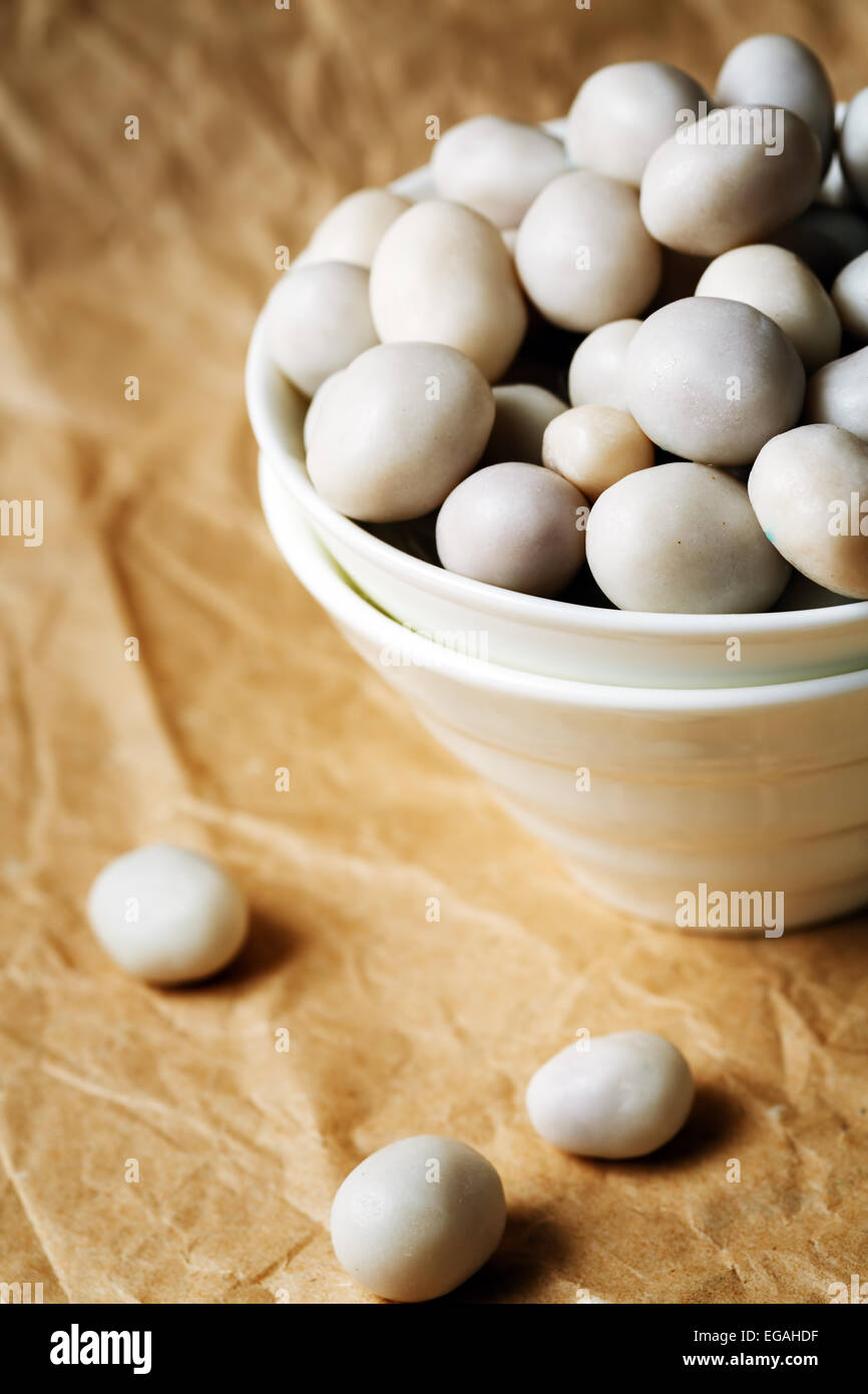 Little white candies like sea pebbles on craft paper background ...