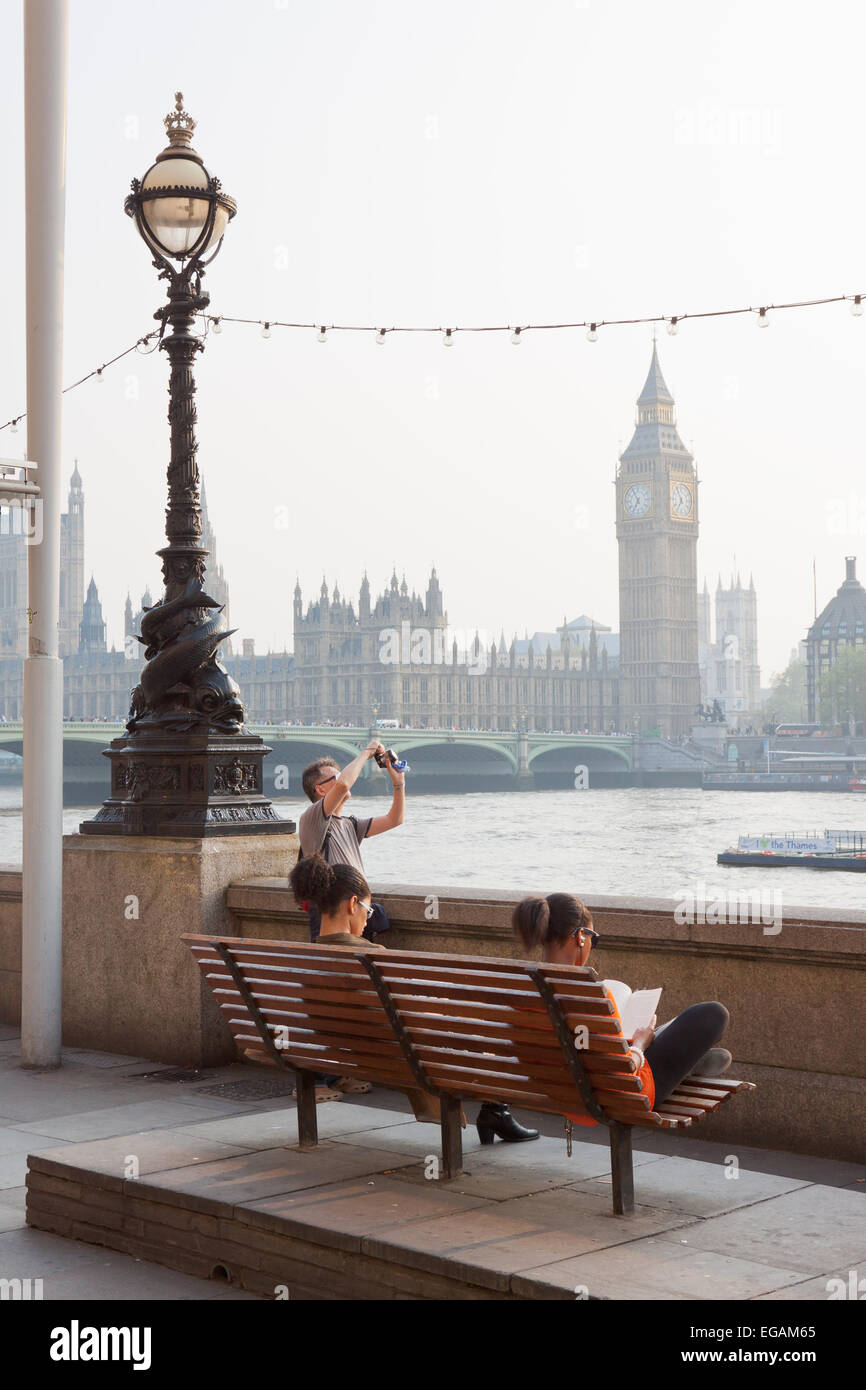 Tourists and visitors relax on the Albert Embankment with Big Ben in ...