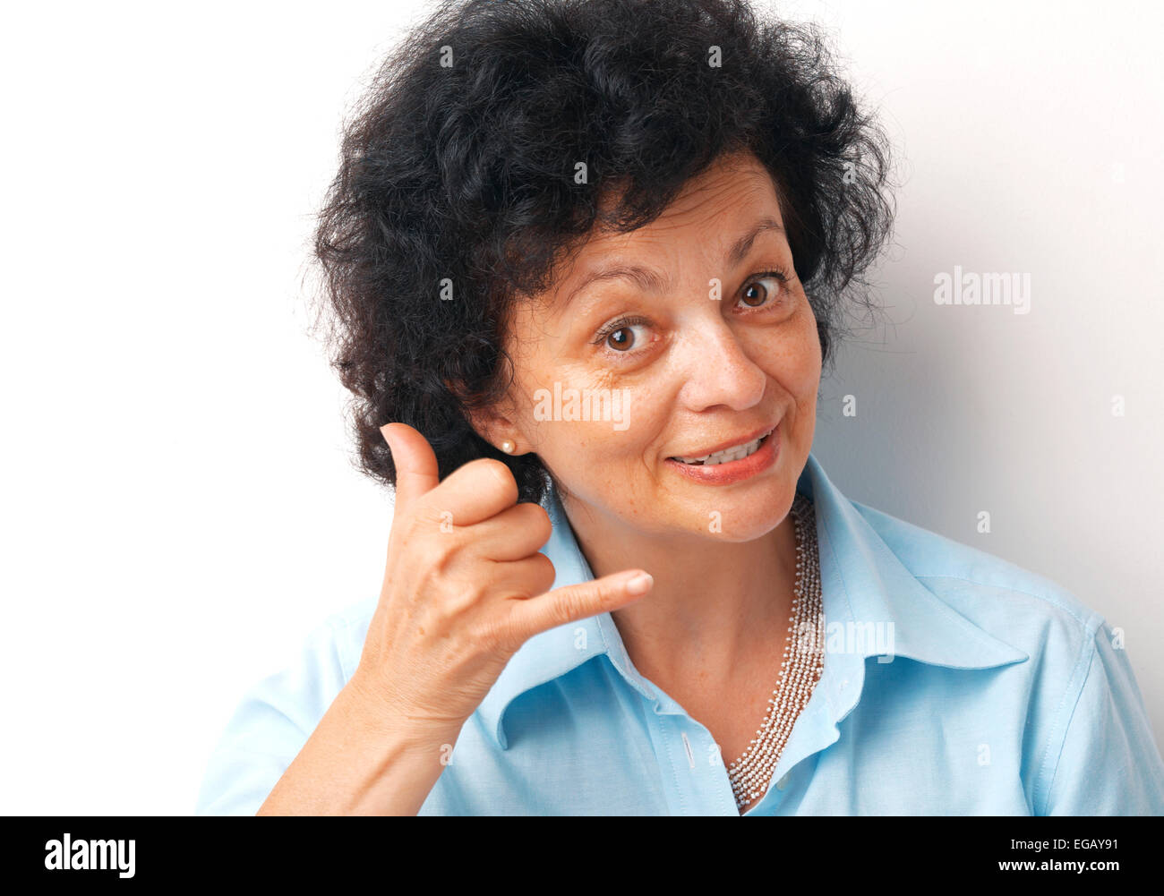 Close-up of an elder woman showing a sign "call me" over white ...