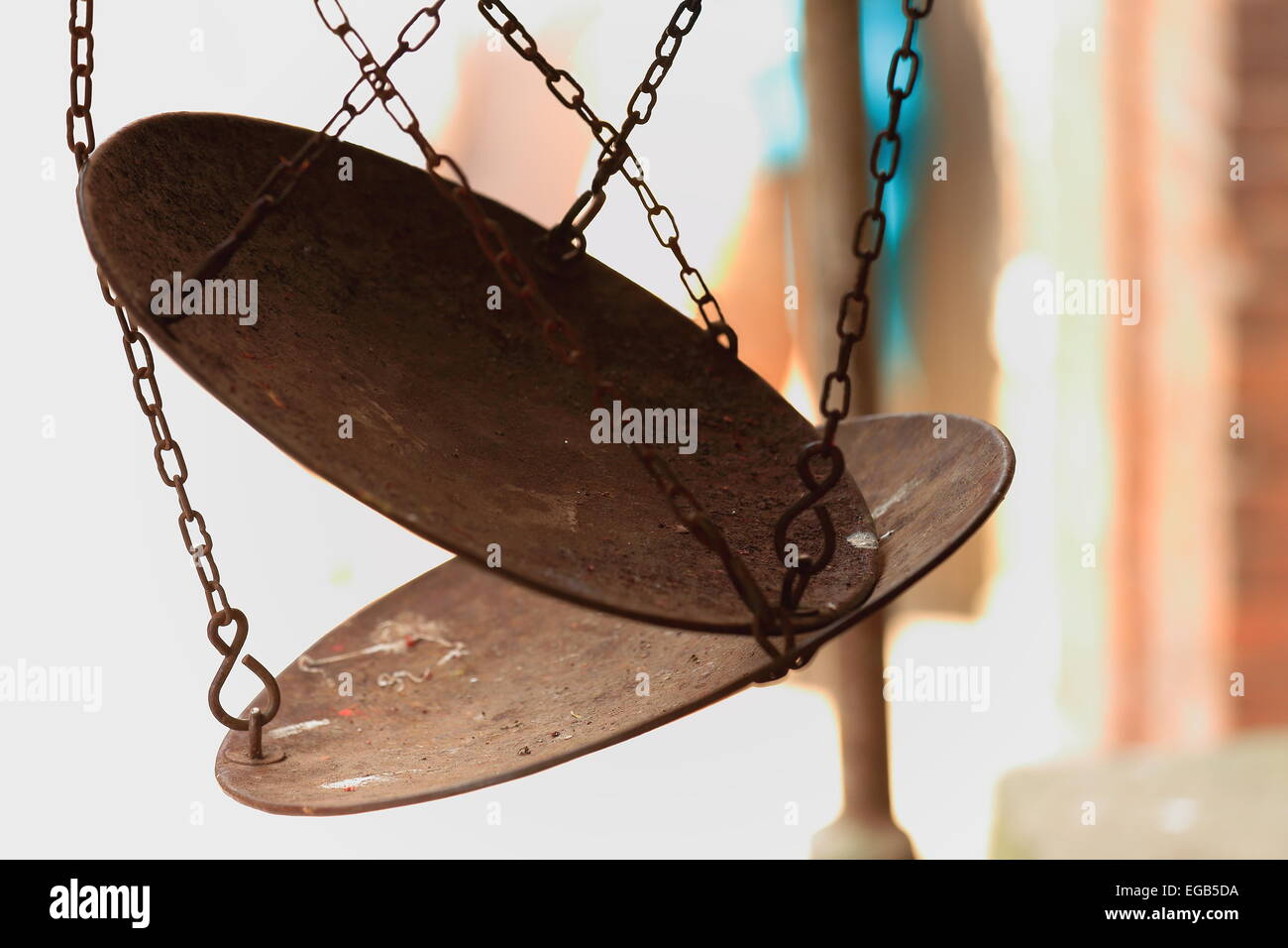 Iron plates of a traditional balance-scales hanging from iron chains ...