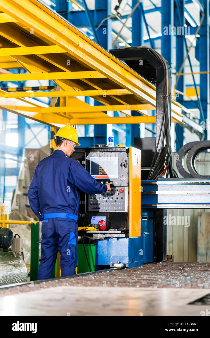 Worker in manufacturing plant at CNC machine control panel Stock Photo ...