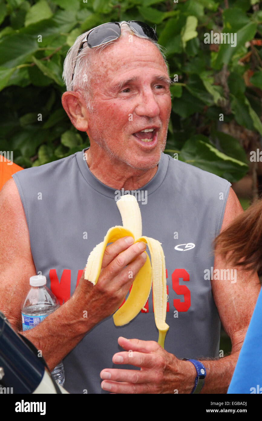 Senior man eating banana after a 5K run or walk sports event ...