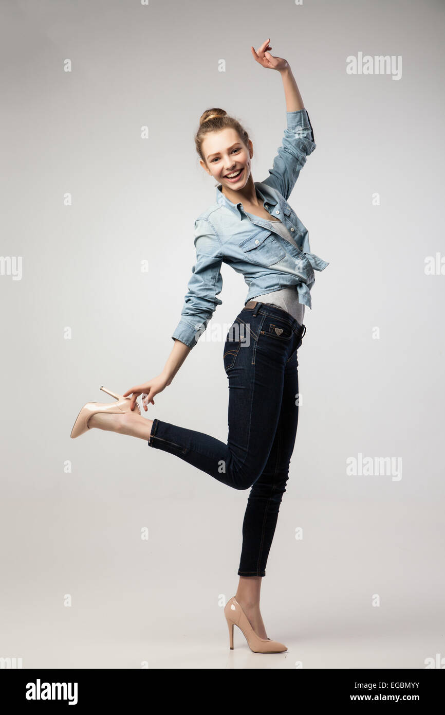 Smiling student girl with one leg and hand up Stock Photo - Alamy