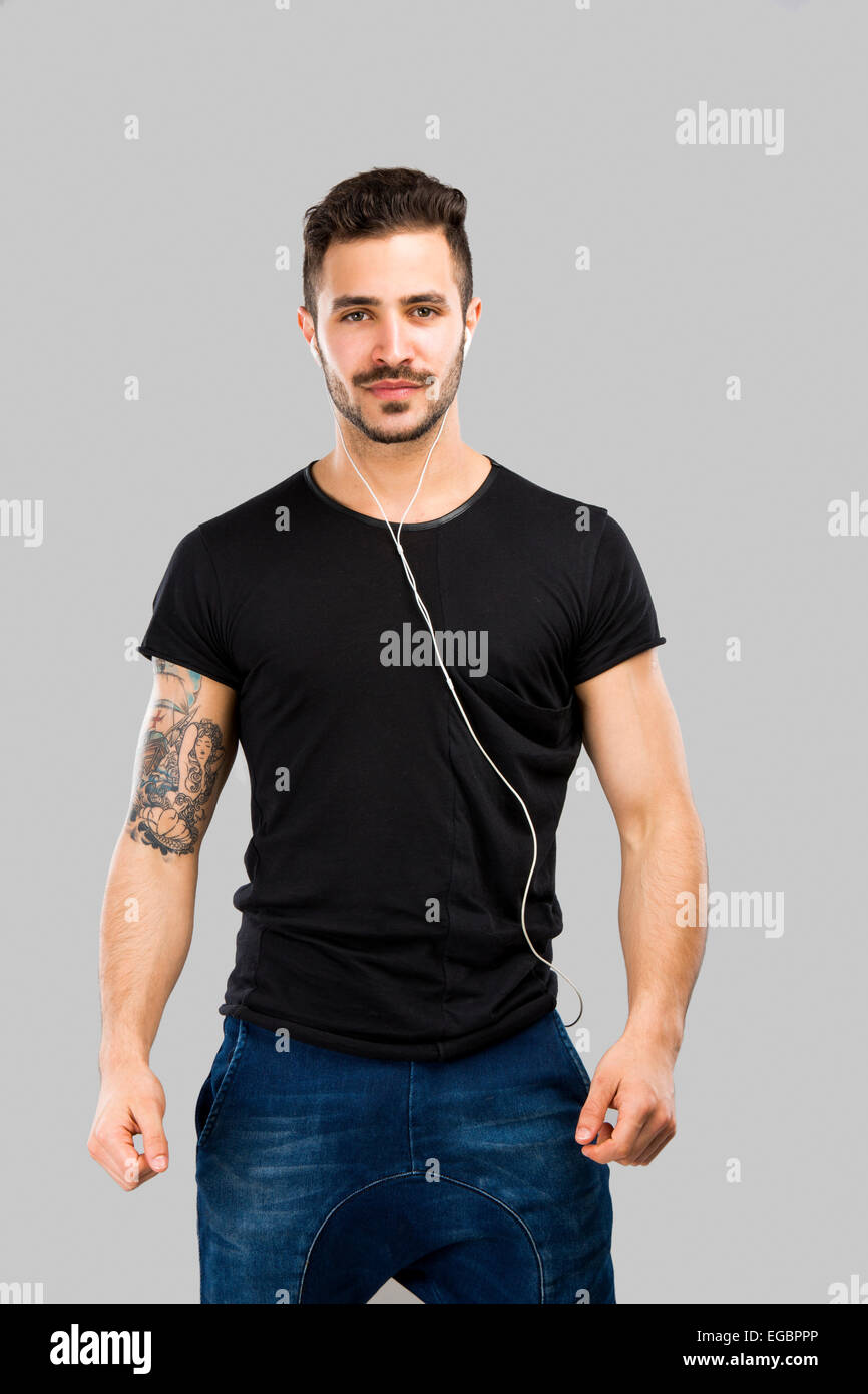 Beautiful latin man listen music over a gray background Stock Photo - Alamy