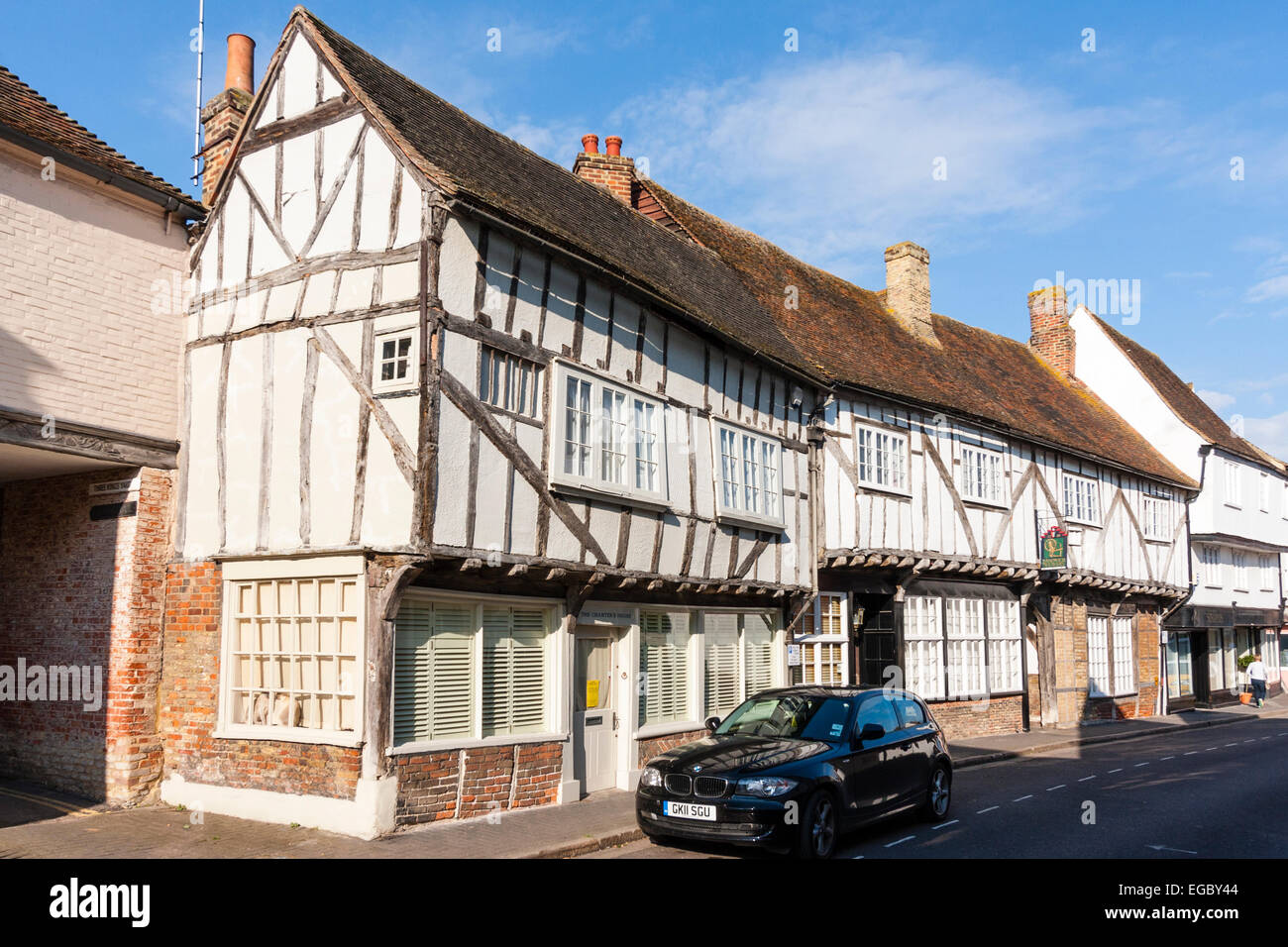 View along sunlit 15th century medieval white plaster and timber frame ...