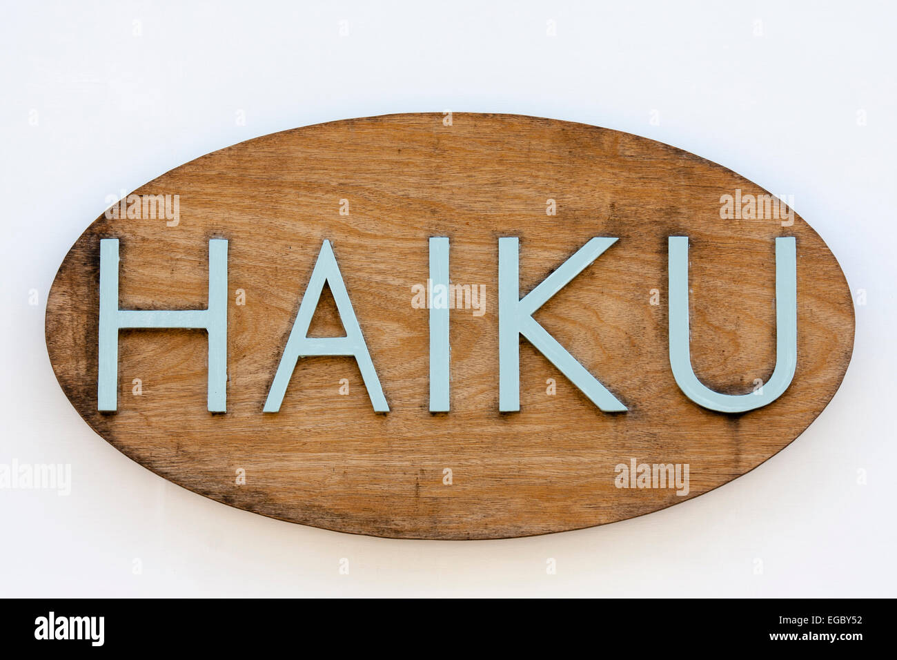 Sign on white wall, 'Haiku' in light blue letters on wooden oval board ...