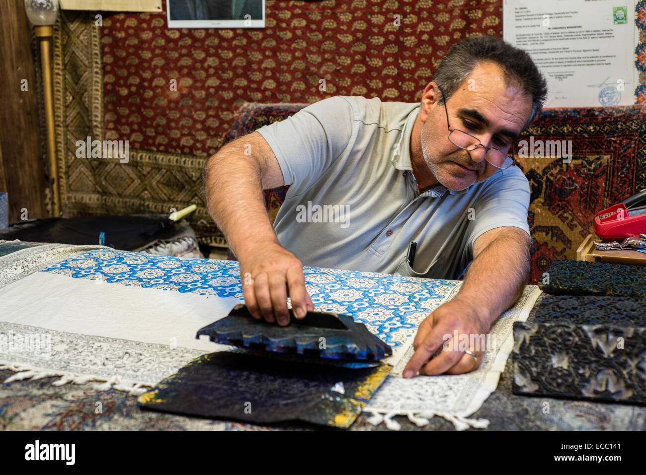 Mohsen, son of Reza Sedighi Fard, master of textile hand printing, stamps pattern on the table ...