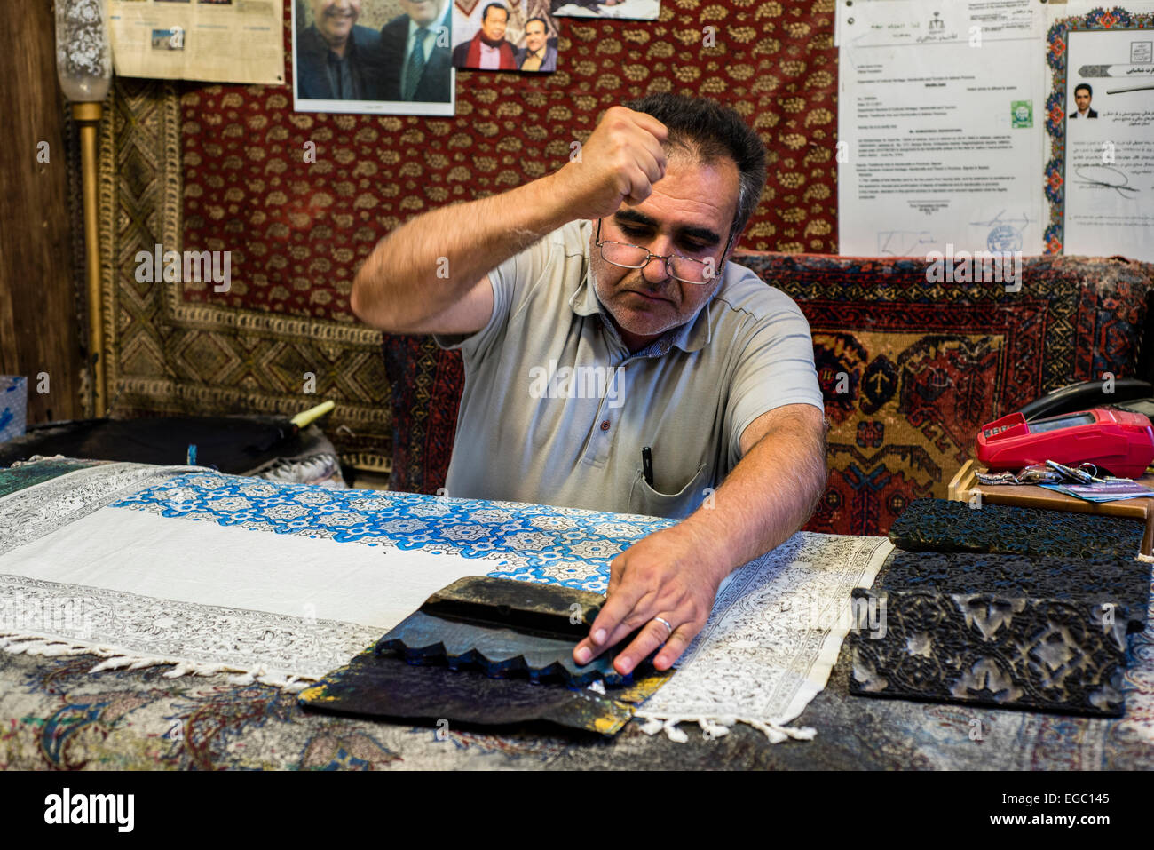 Mohsen, son of Reza Sedighi Fard, master of textile hand printing, stamps pattern on the table ...