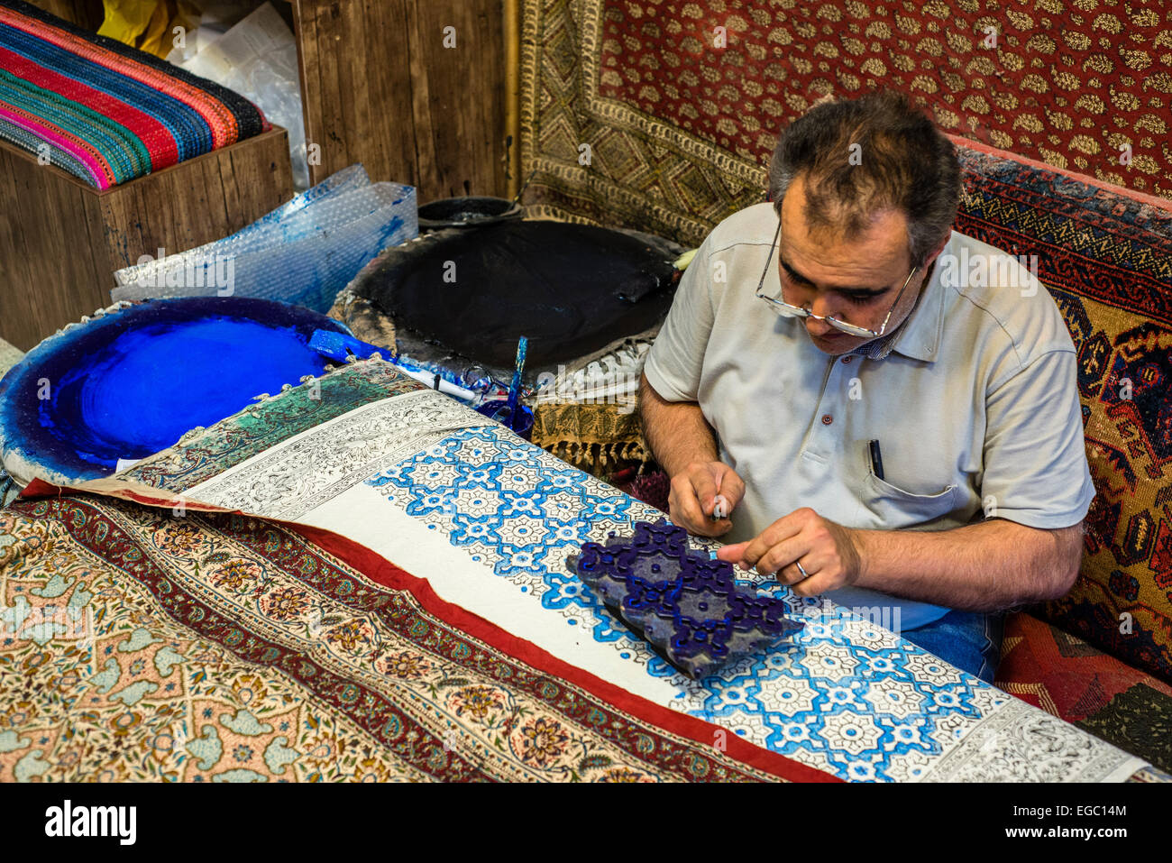 Mohsen, son of Reza Sedighi Fard, master of textile hand printing, stamps pattern on the table ...