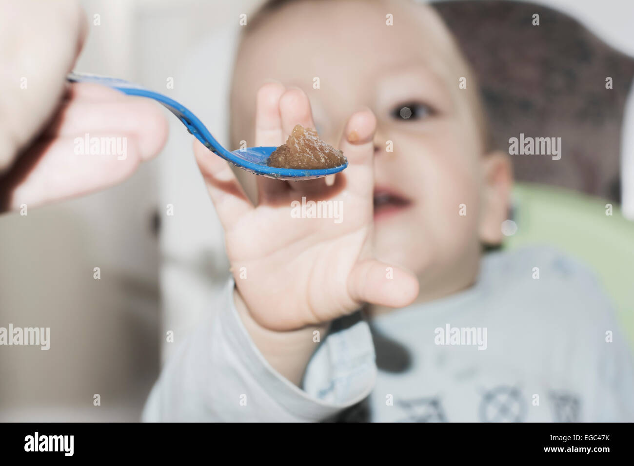 Mother's hand is feeding baby and he refuse it Stock Photo - Alamy