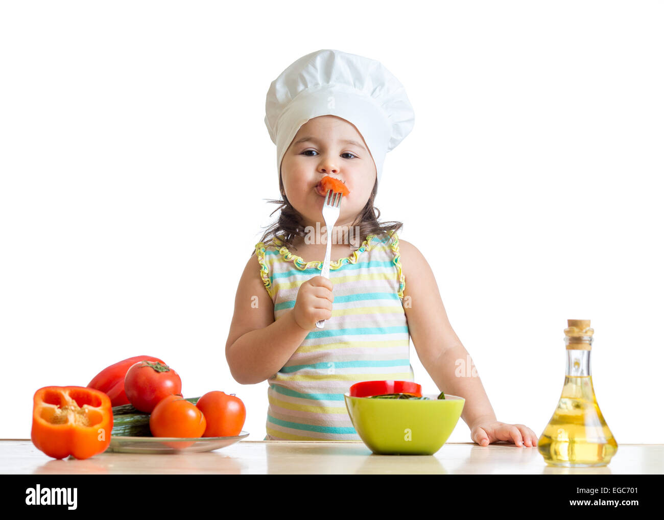 kid girl in cook hat eating vegetables Stock Photo - Alamy