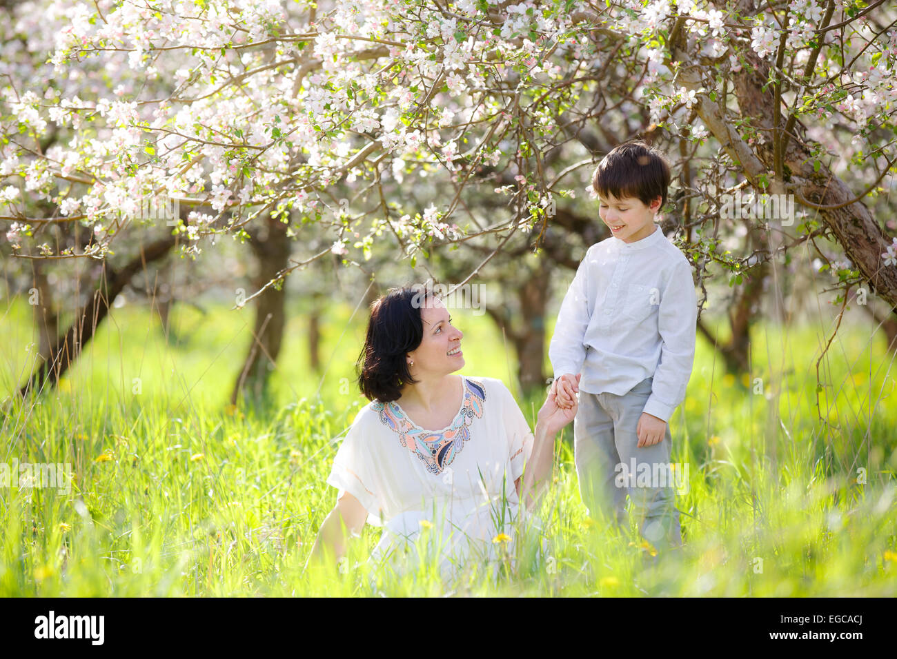 Happy woman and child in spring apple garden Stock Photo - Alamy