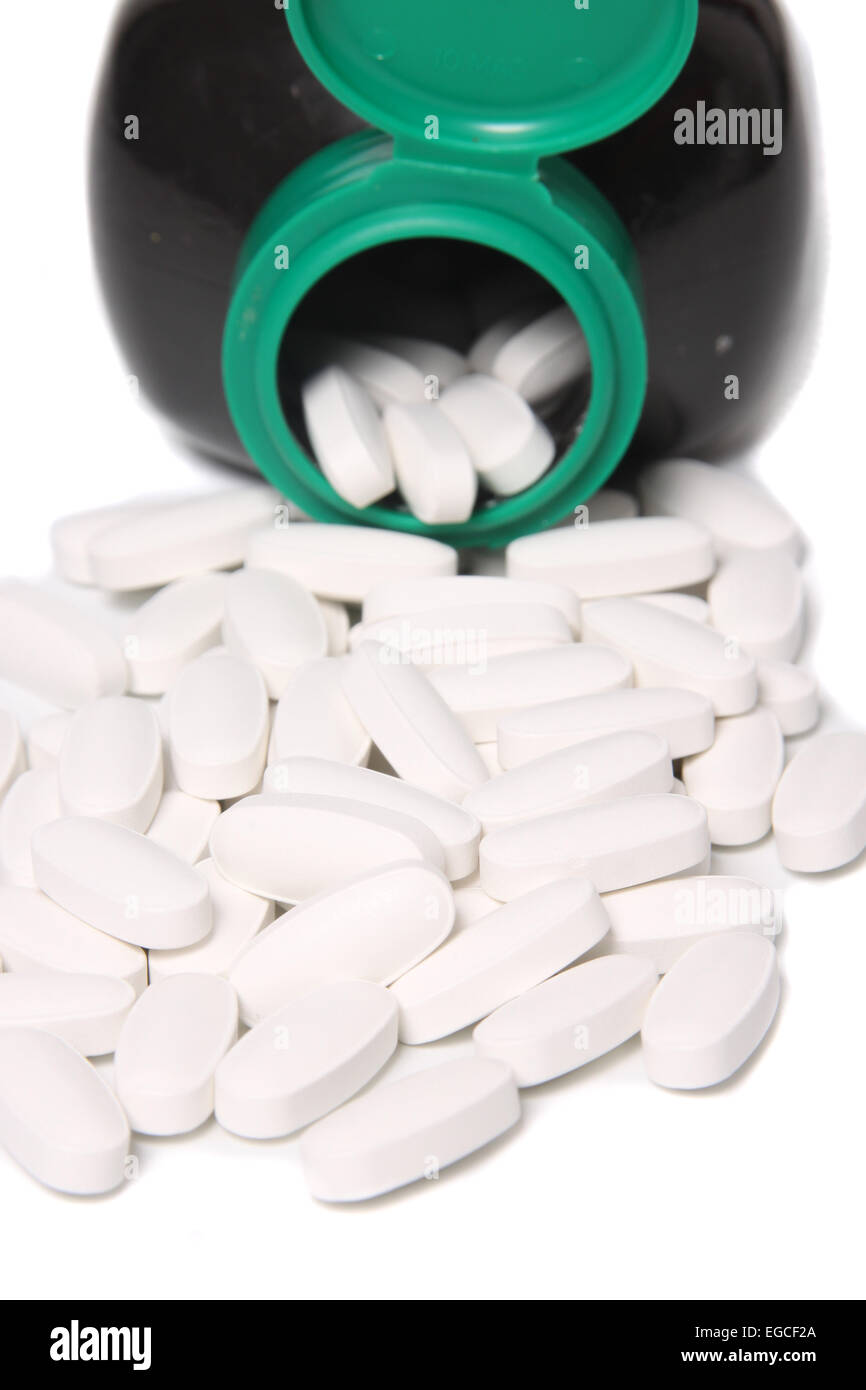 White calcium vitamins spilling from a bottle on a white background ...