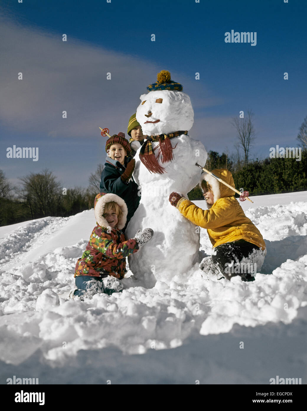 1970s FOUR CHILDREN MAKING A SNOWMAN Stock Photo - Alamy