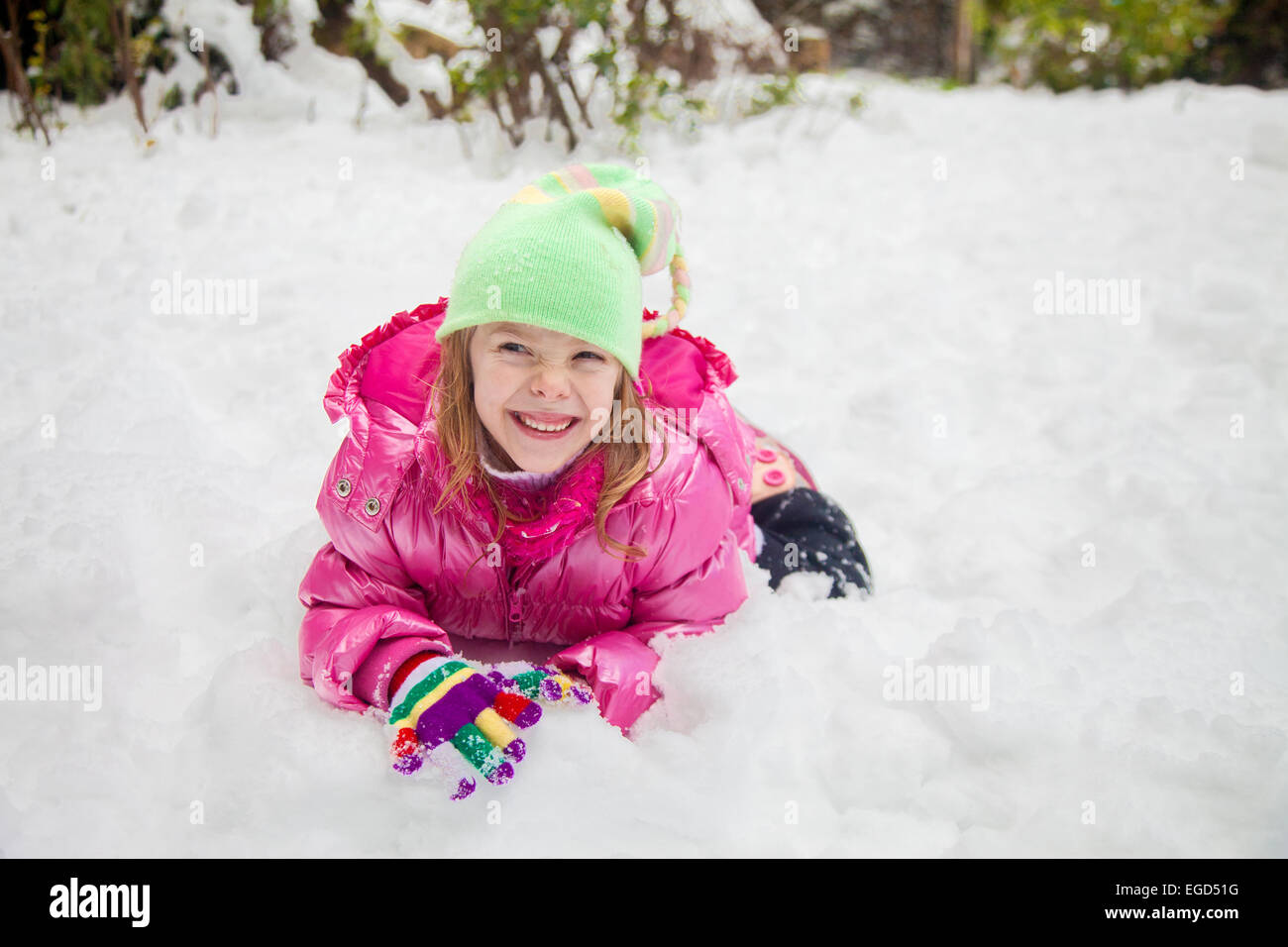 Laughing little girl making faces while playing in the snow at her ...