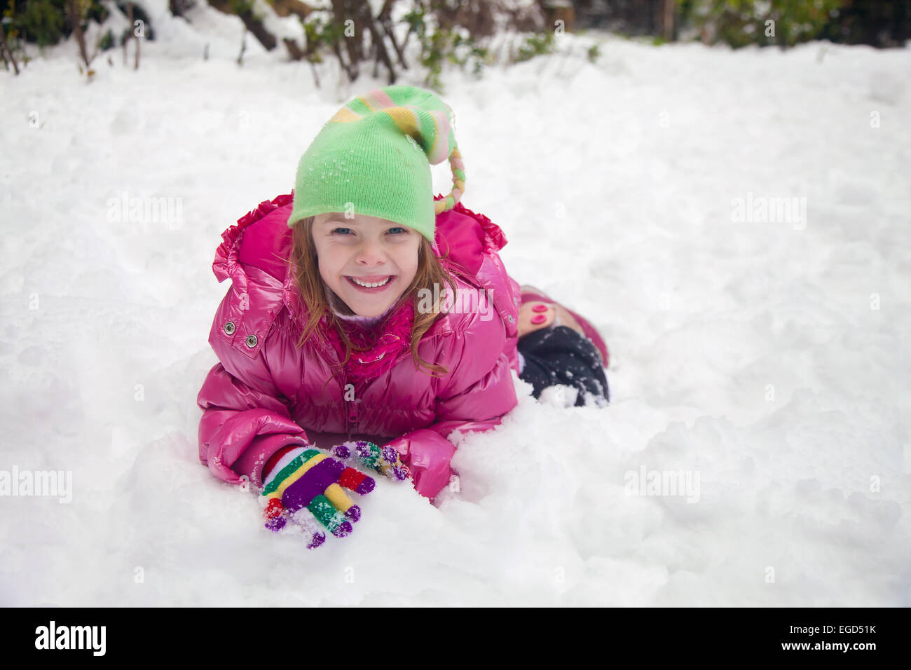 Happy little girl sitting in the snow making a snow ball (after ...