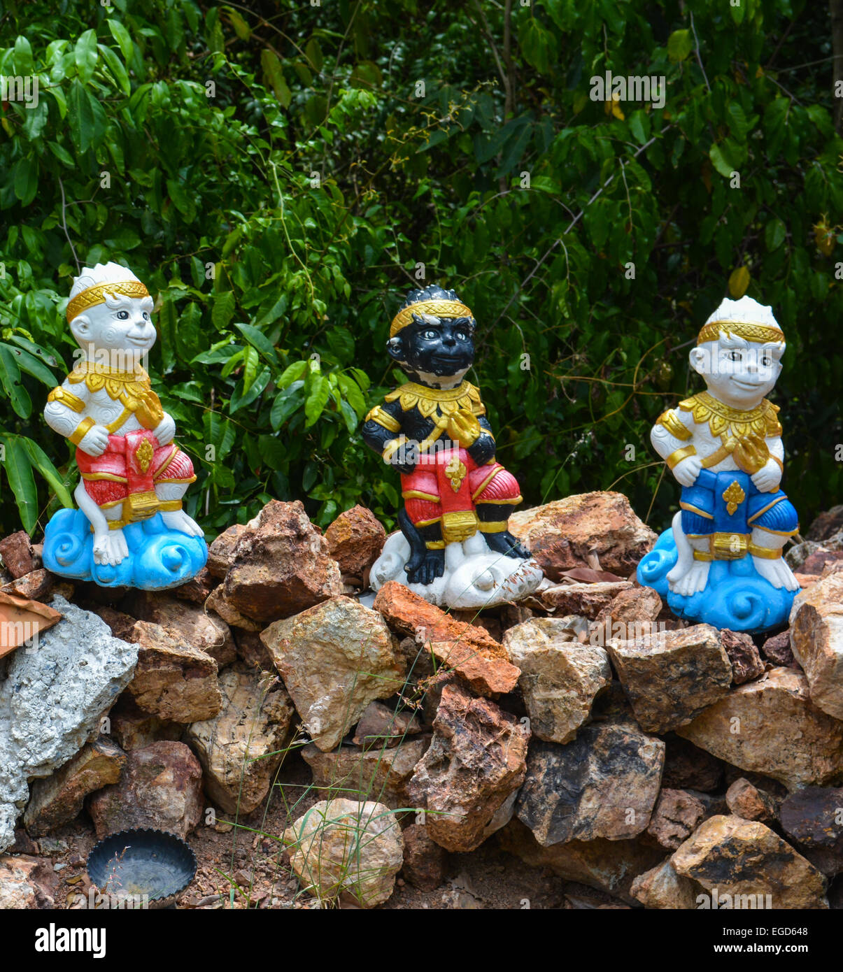 Three multi-colored statues of monkeys on the rocks Stock Photo - Alamy