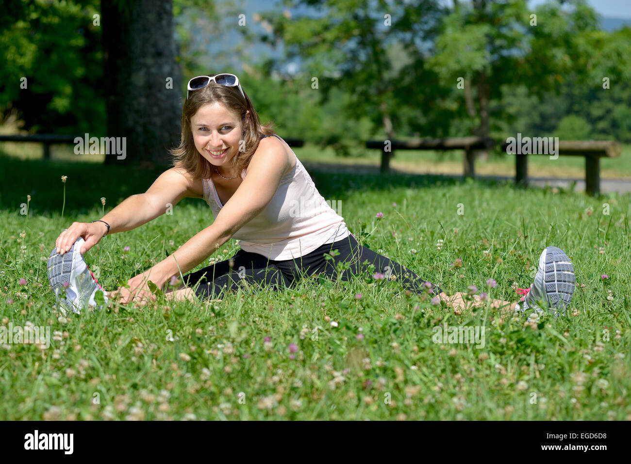 sporty young woman makes stretching exercises on grass Stock Photo - Alamy