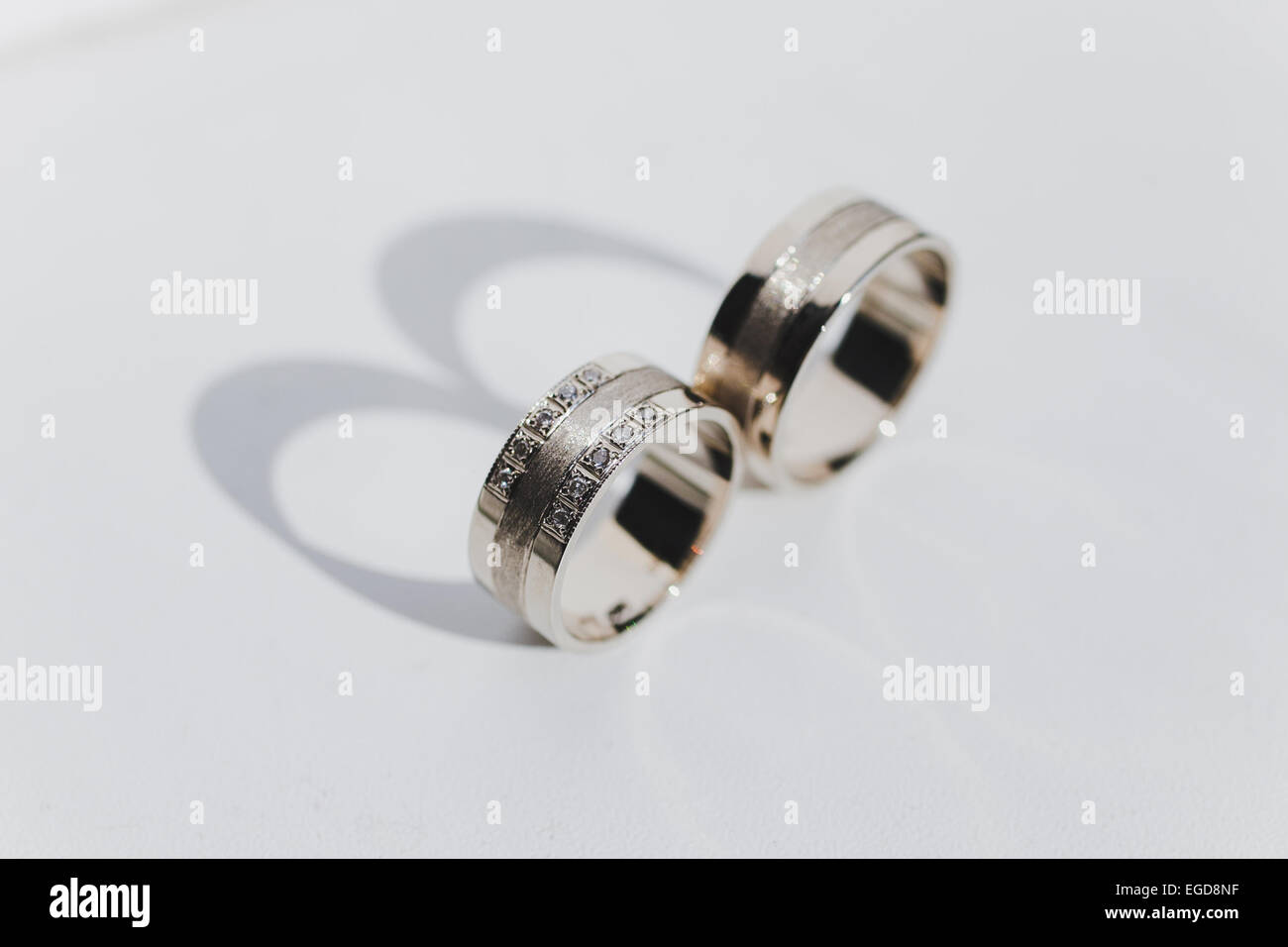 Two wedding rings laying on white table Stock Photo - Alamy