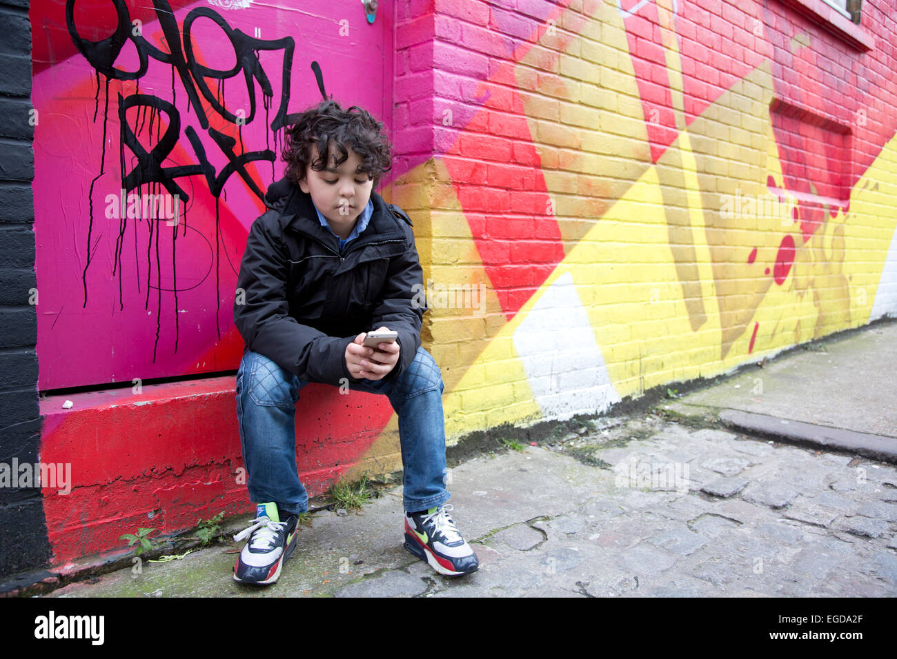 Kid sitting on step texting Stock Photo - Alamy