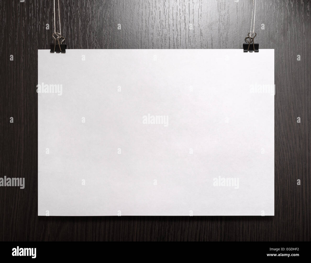 Blank horizontal paper poster hanging on dark wooden background. Front ...