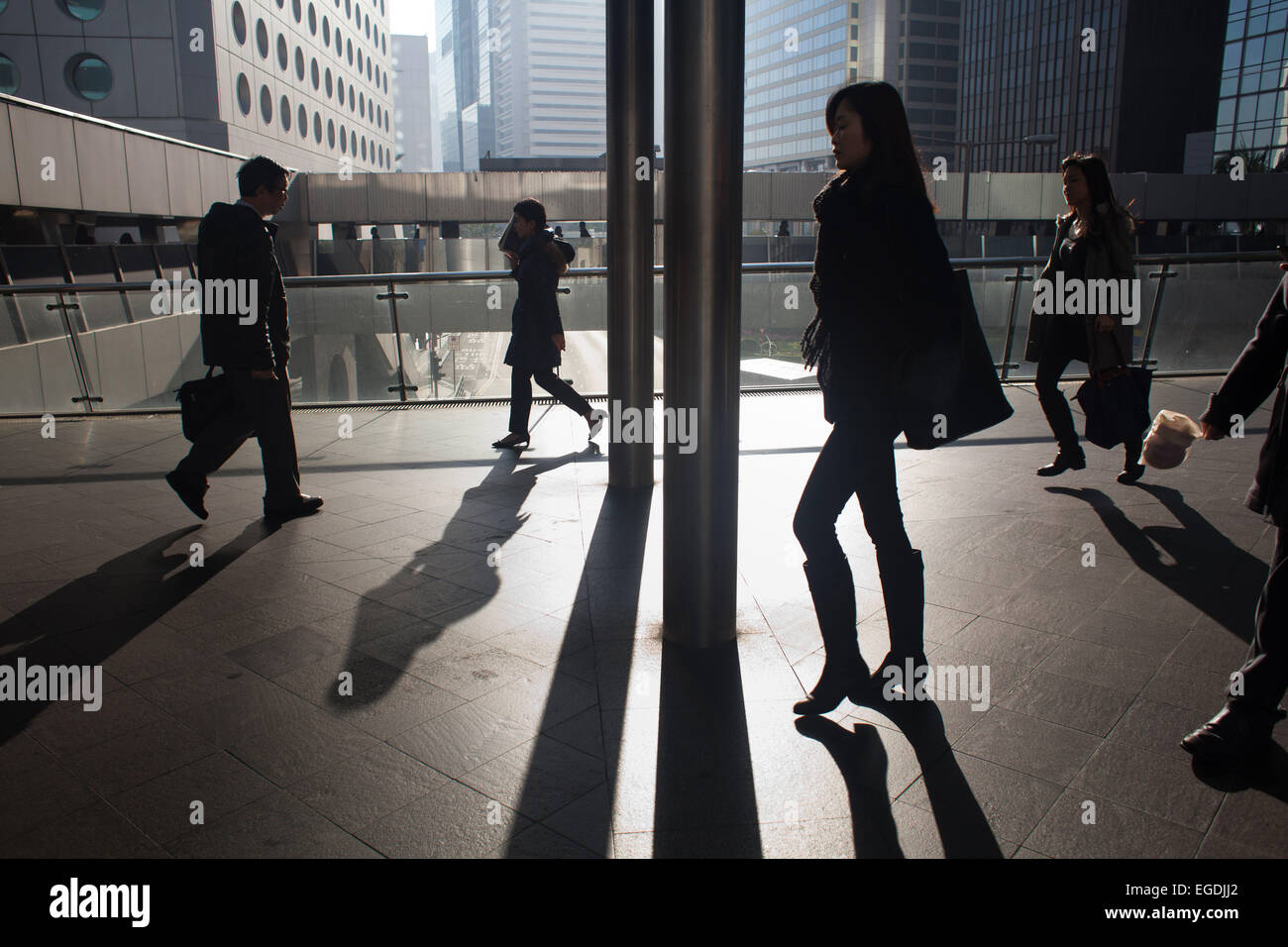 Commuters rush along in the sun and shadow on a fly-over in Central on ...