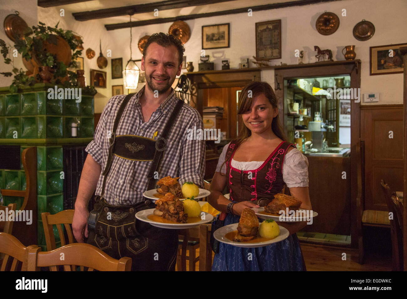 Friendly waiter and waitress serving plates of pork with dumplings ...