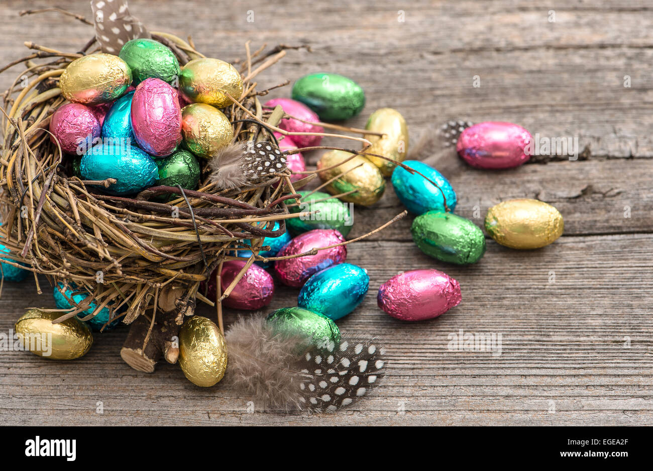 Multicolor chocolate easter eggs in nest on wooden background. Festive ...