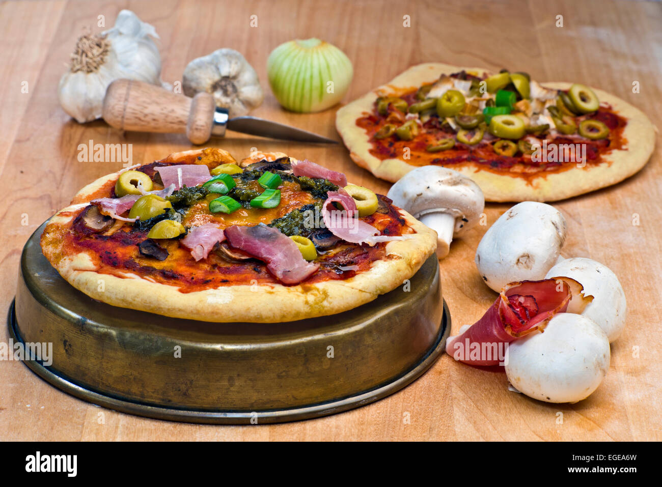 Mini pizzas with prosciutto,mushrooms, olives, pesto and cheese topping ...