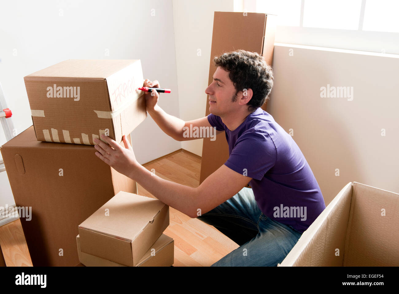 Young man packing boxes Stock Photo - Alamy