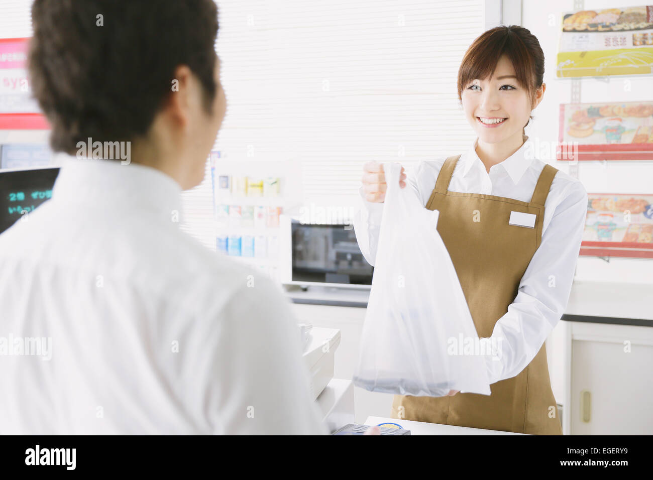 Young Japanese woman working at convenience store Stock Photo - Alamy