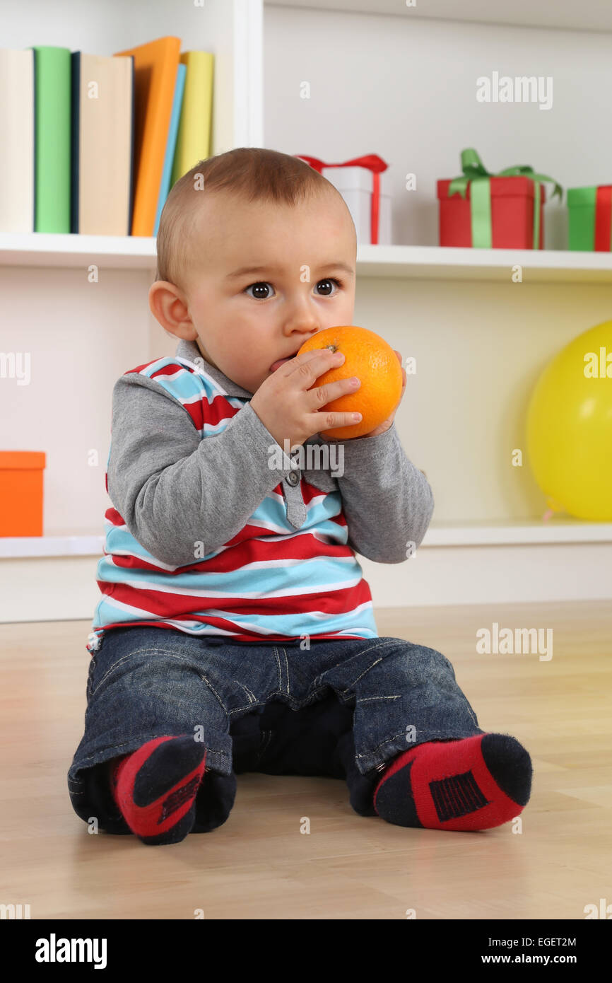 Cute little baby boy child eating orange fruit Stock Photo - Alamy