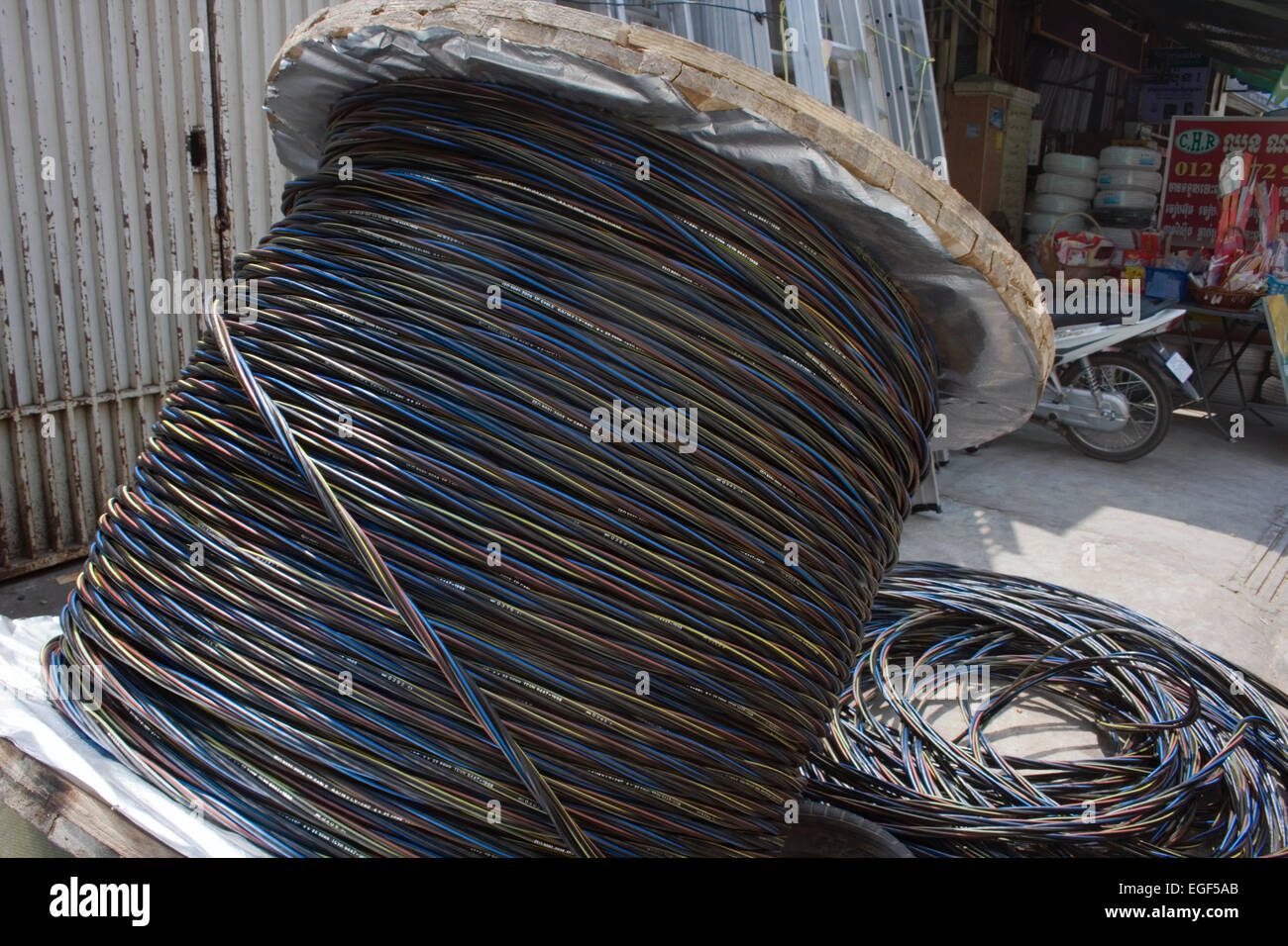 A spool wrapped with electrical wire and cable rest on a city sidewalk ...