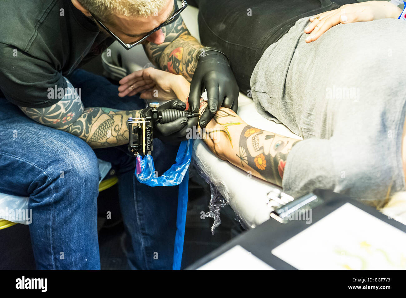 A man being tattooed on his arm at the Brighton Tattoo Convention Stock ...