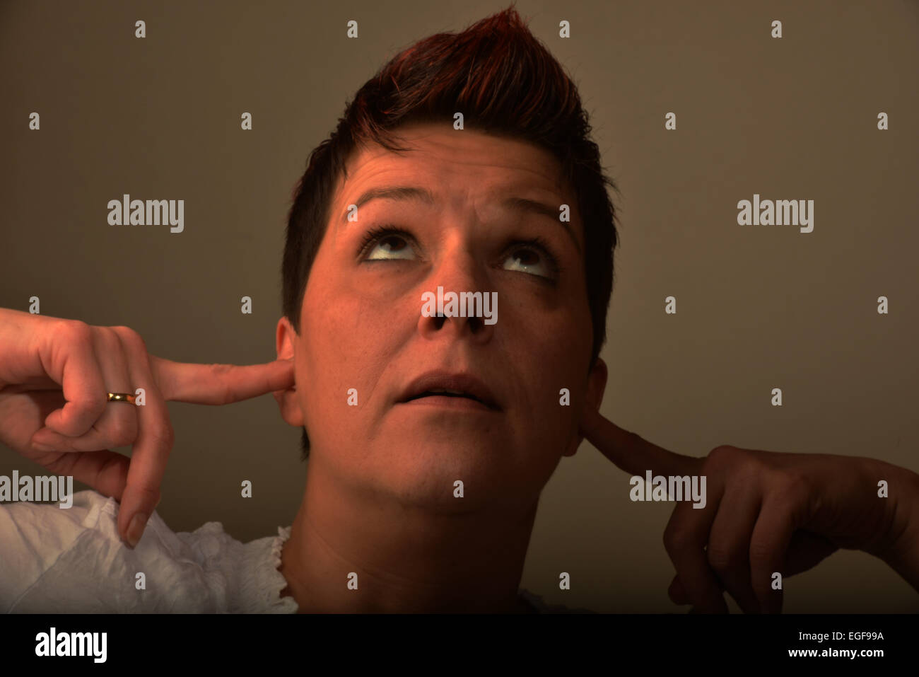 A young woman with a distressed face is holding her ears. Photo on 03 ...